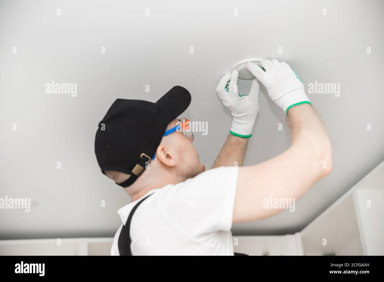 Working electrician changes light bulb and installs wiring for lamp in ...