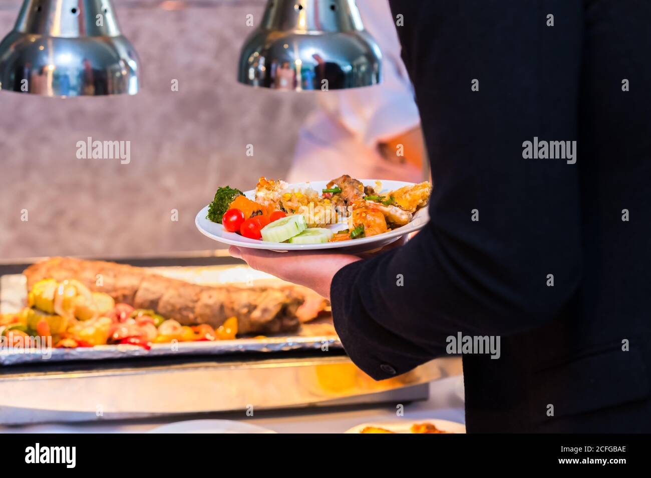 A steak pork, tomato, vegetable are in the dish. A man hold dish in the ...