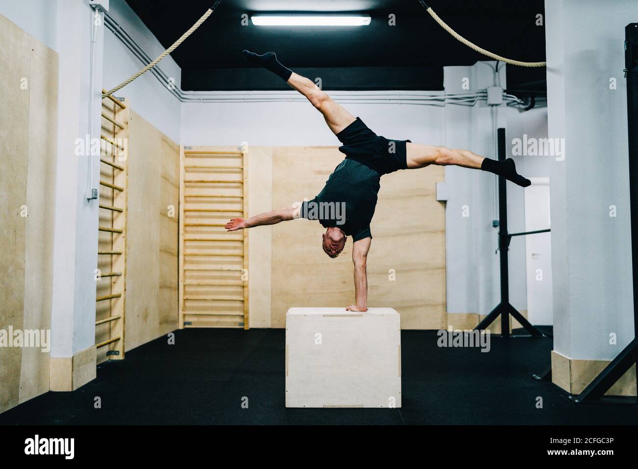 Flexible male gymnast in active wear performing acrobatic element in ...