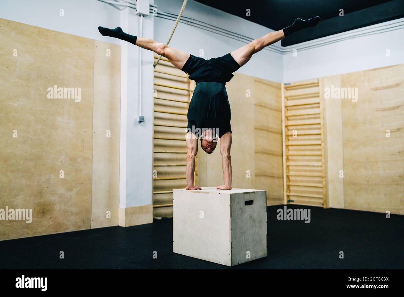 Flexible male gymnast in active wear performing acrobatic element in ...