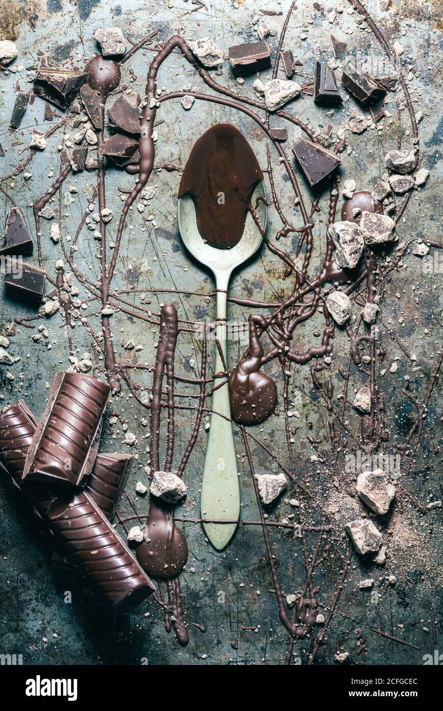 From above top view spoon with chocolate spilled over rustic metal ...