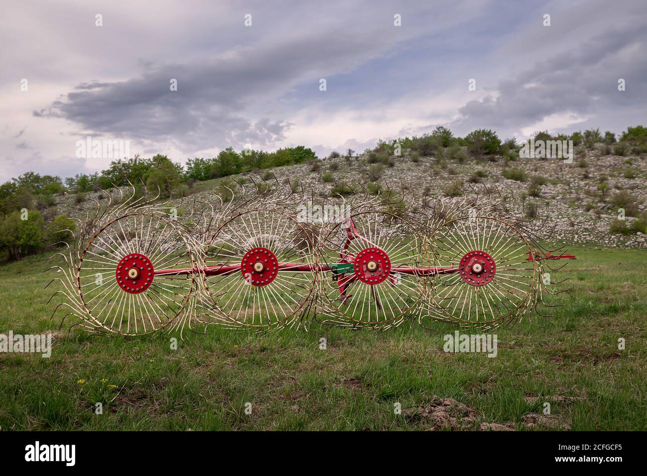 Old, red, rusty, vantage hay collector on a green grass in the spring ...
