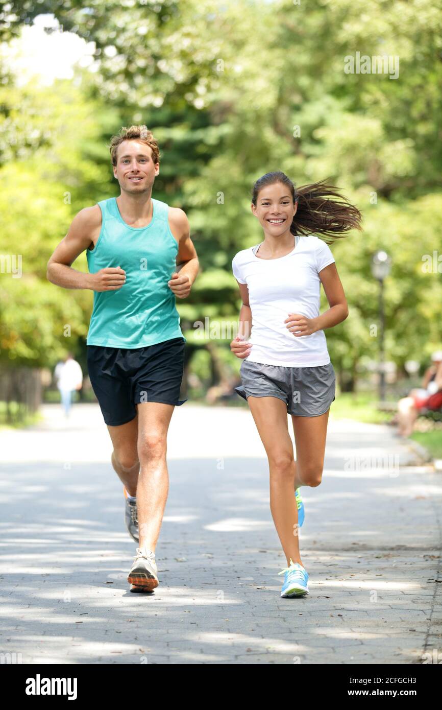 Running couple training outdoors in park fit happy Stock Photo - Alamy