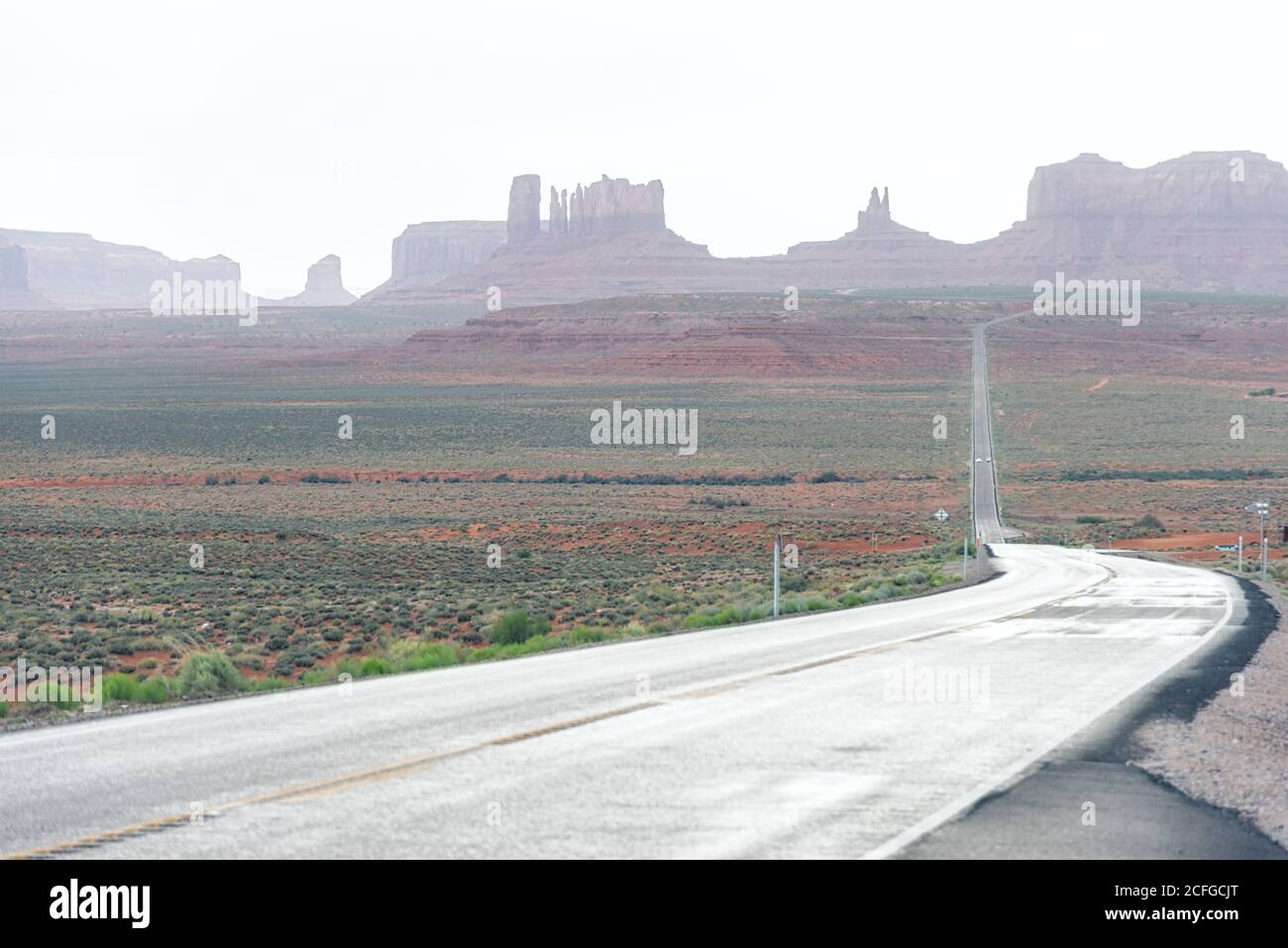 Rural highway at dusty field with power line and remote mountain range ...