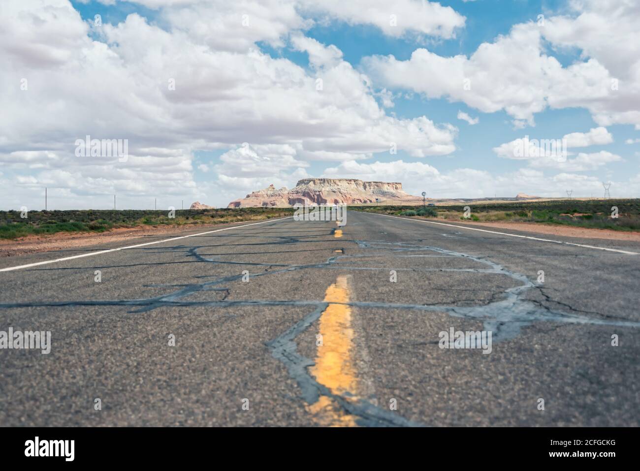 Rural highway at dusty field with power line and remote mountain range ...