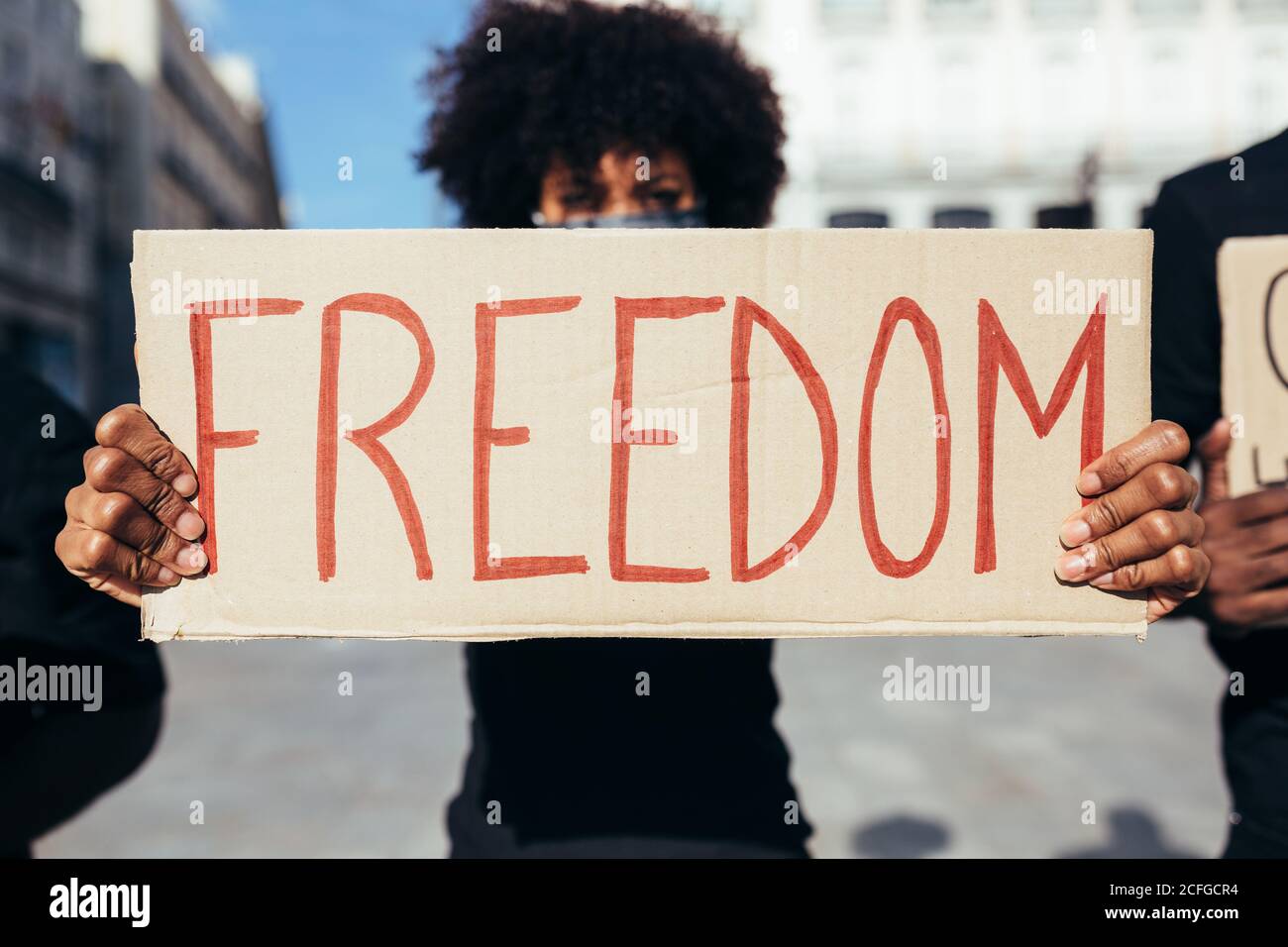 Afro Woman protesting at a rally for racial equality holding a "Freedom ...