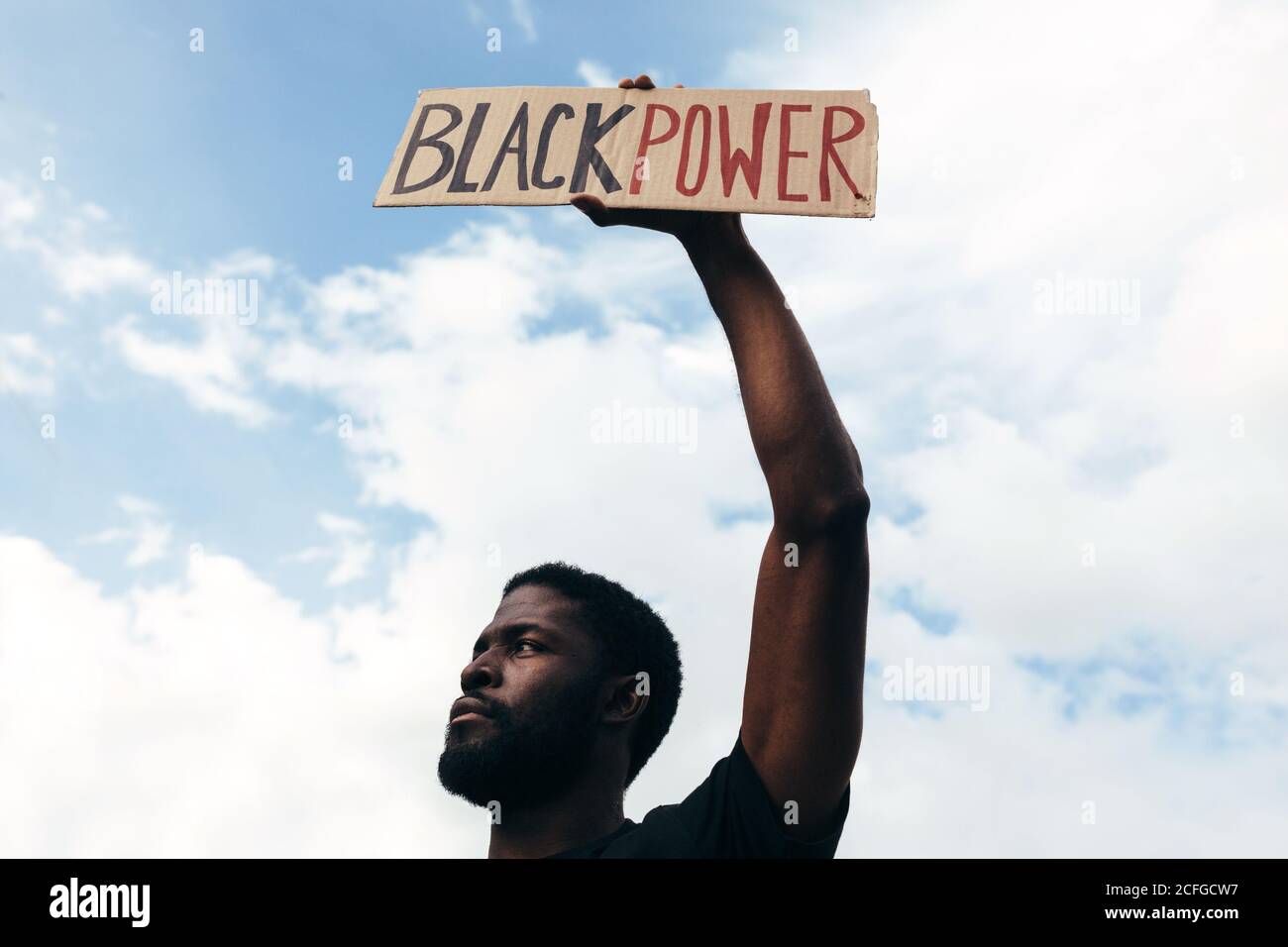 man protesting at a rally for racial equality holding a "Black Power ...