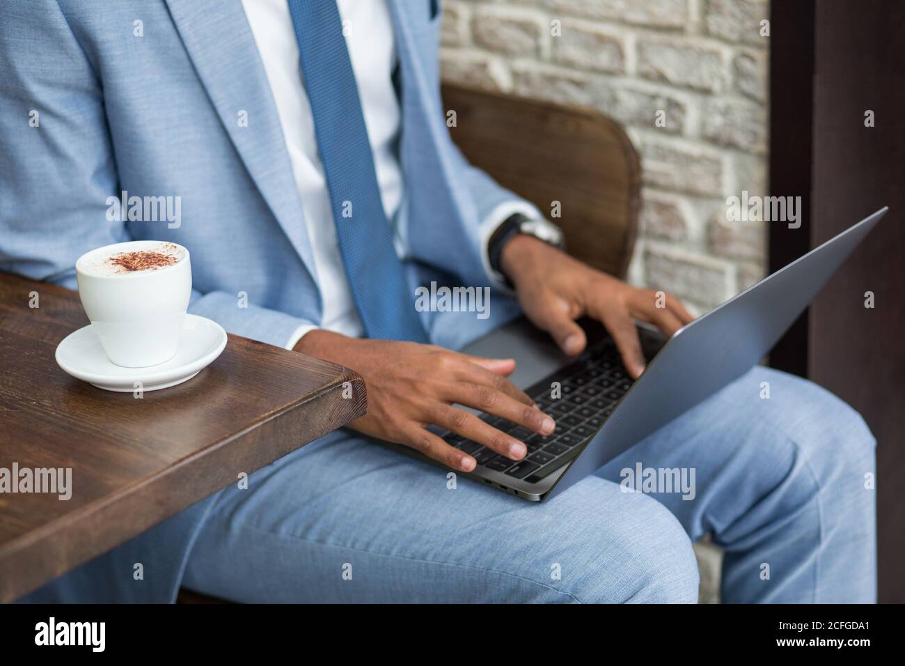 faceless shot of black man in blue suit sitting with cup of coffee at ...