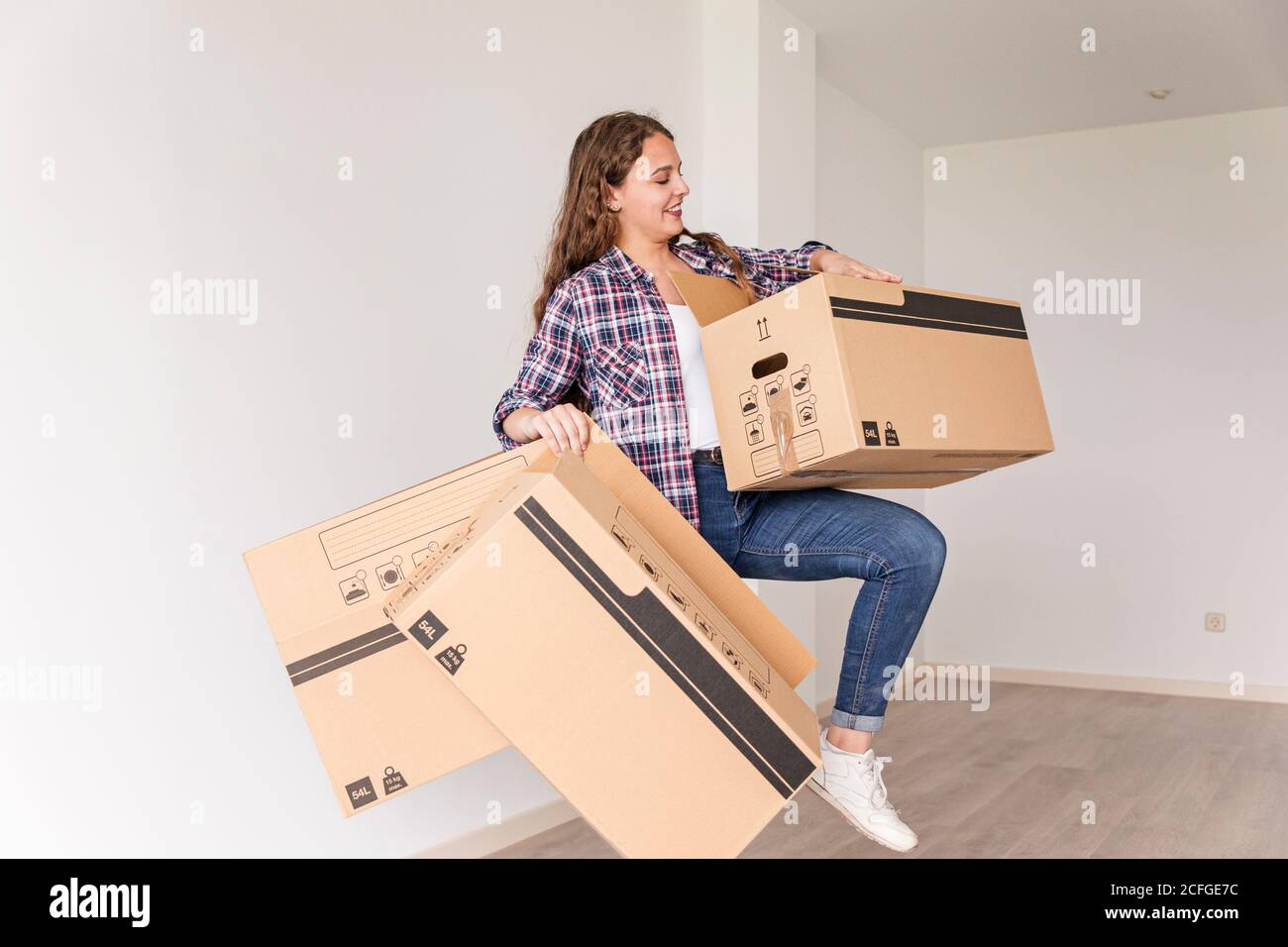 Young cute female in casual wear holding many big carton boxes in empty ...