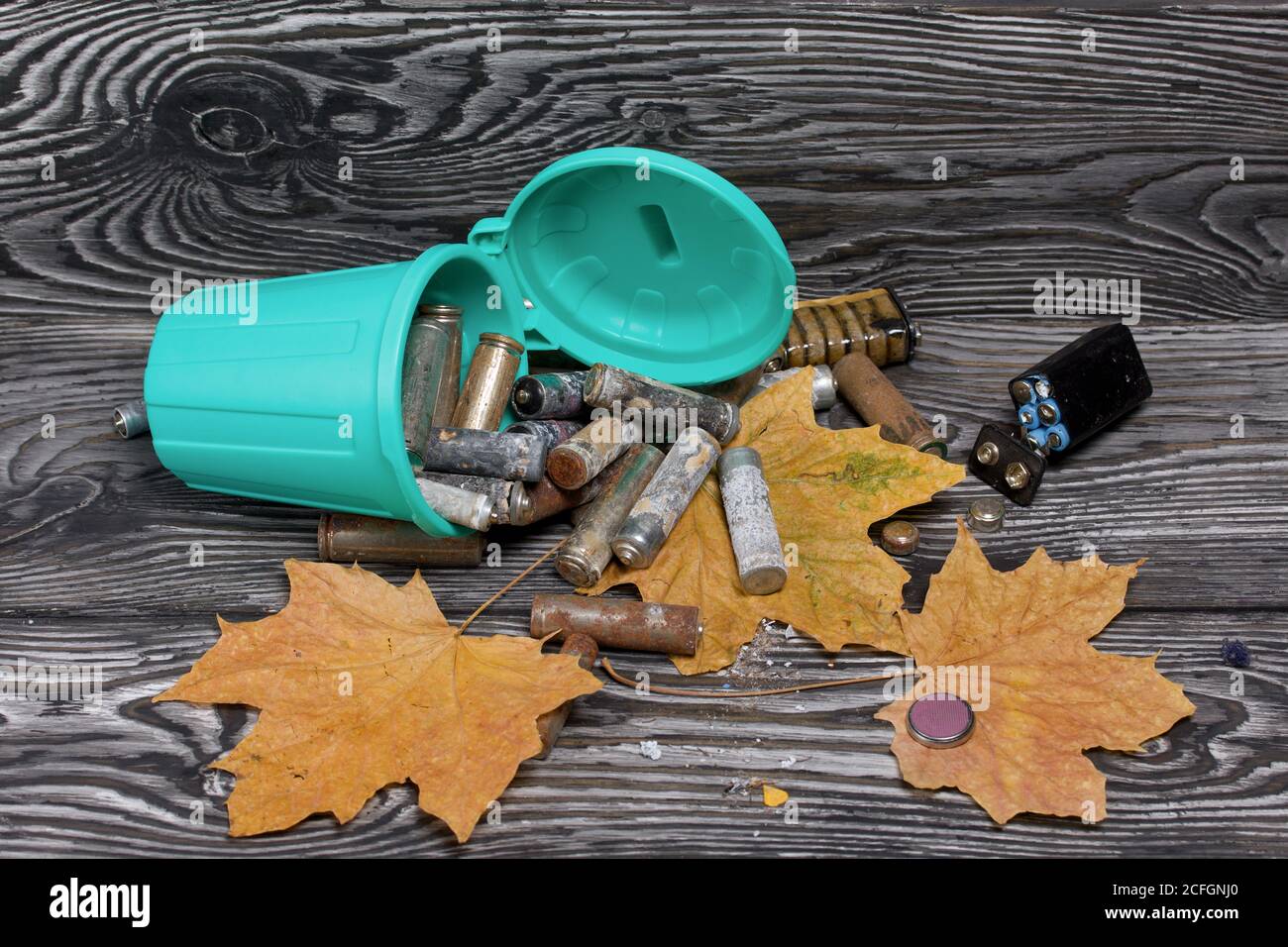 Corroded used batteries. They lie in and around an overturned trash can ...