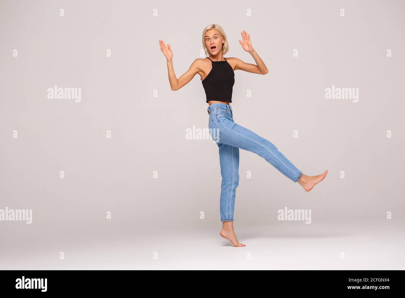 Freestyle. Young blonde woman in jeans and top making step falling down ...