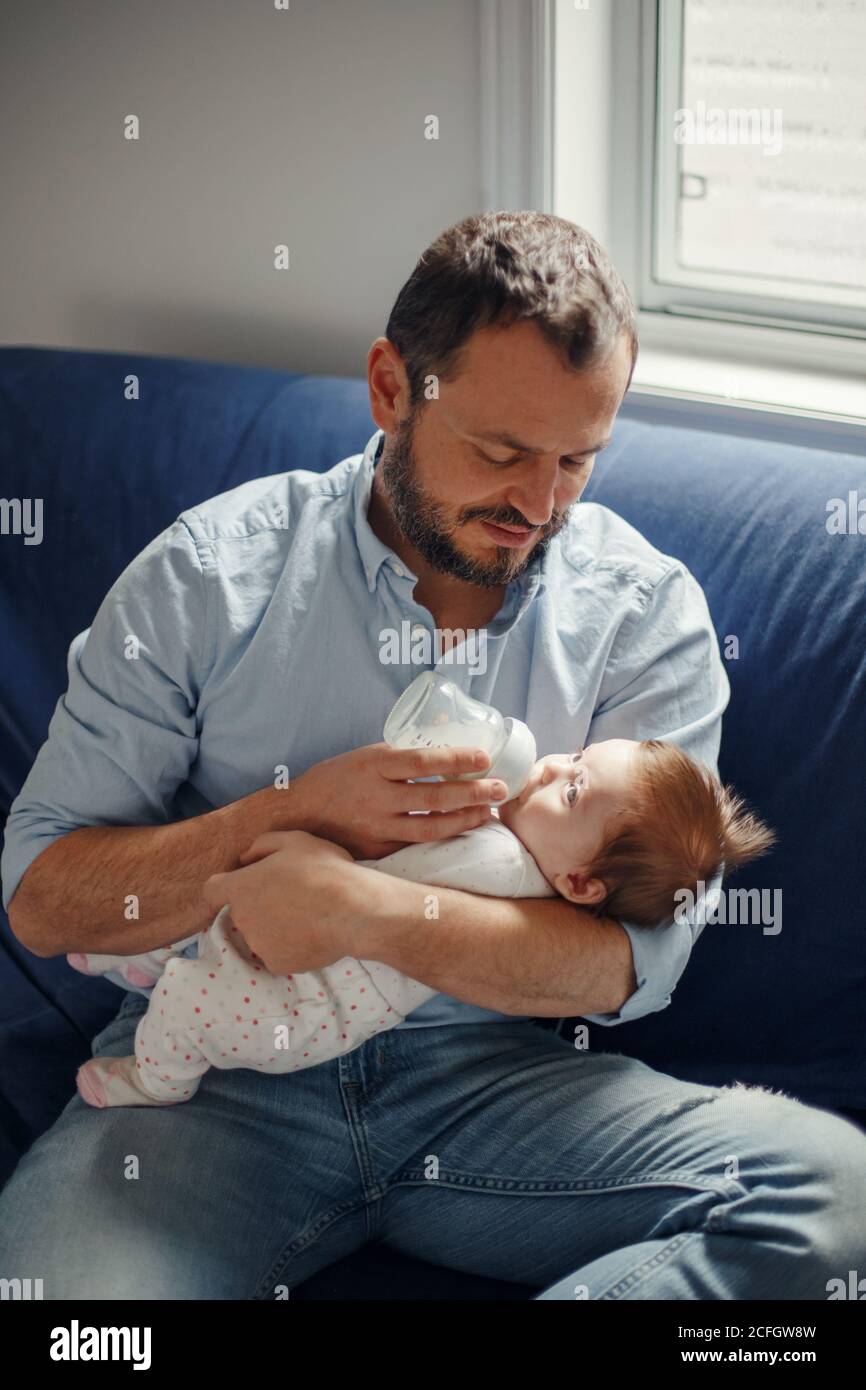 Middle age Caucasian father feeding newborn baby from bottle with milk ...