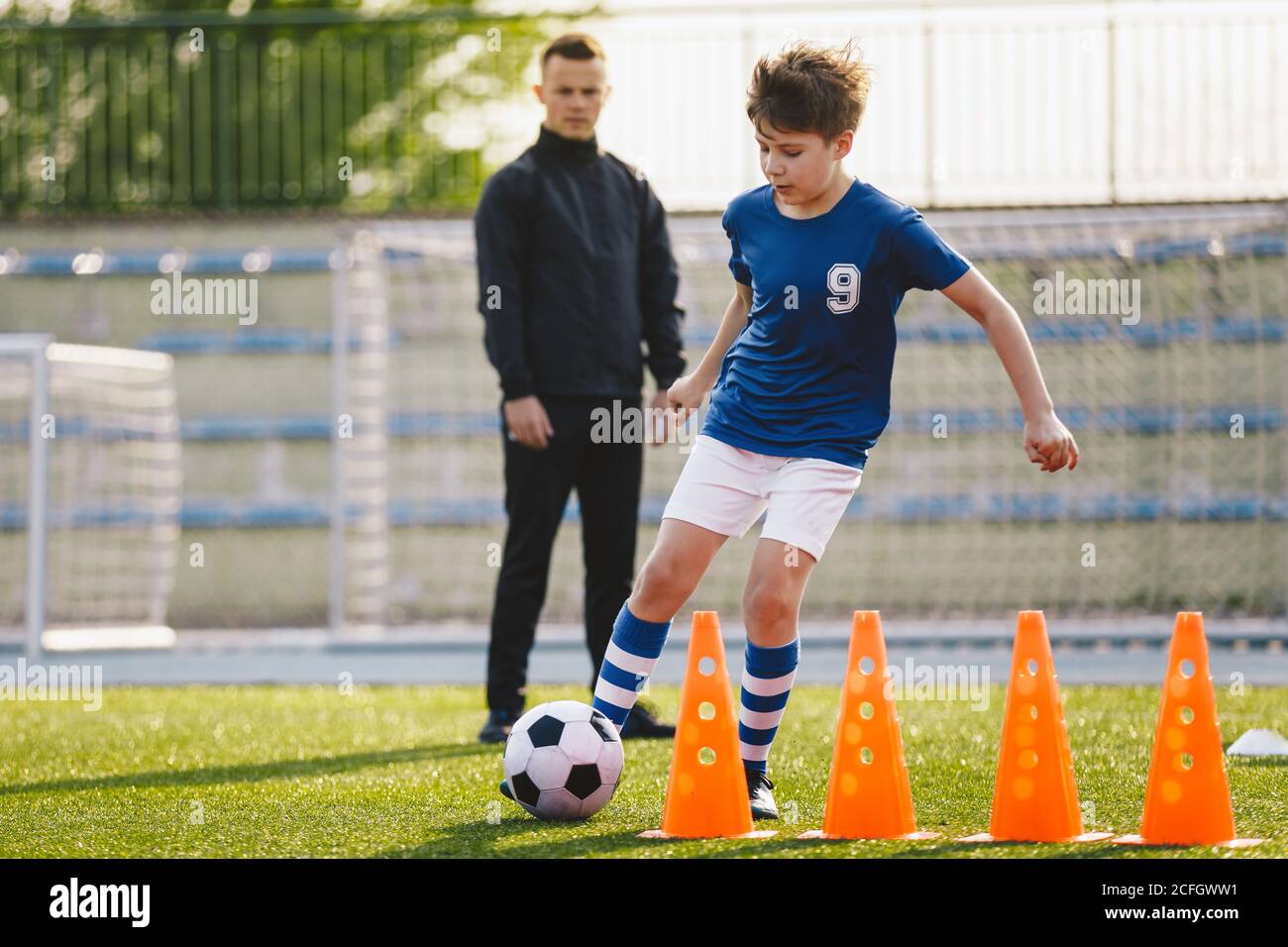 Kid soccer player dribbling through cones. Boy in soccer uniform ...