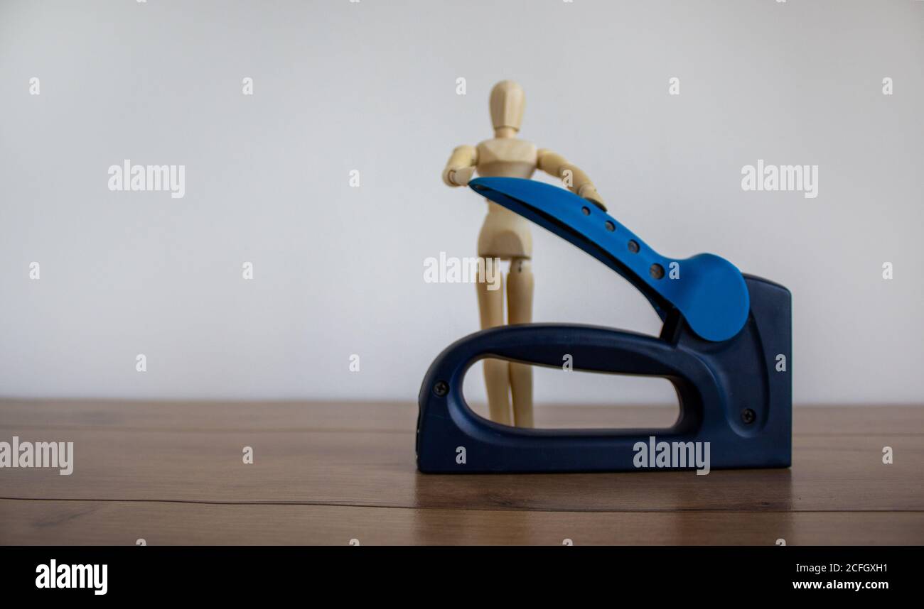 A construction stapler on a wooden table. Wooden model of human ...