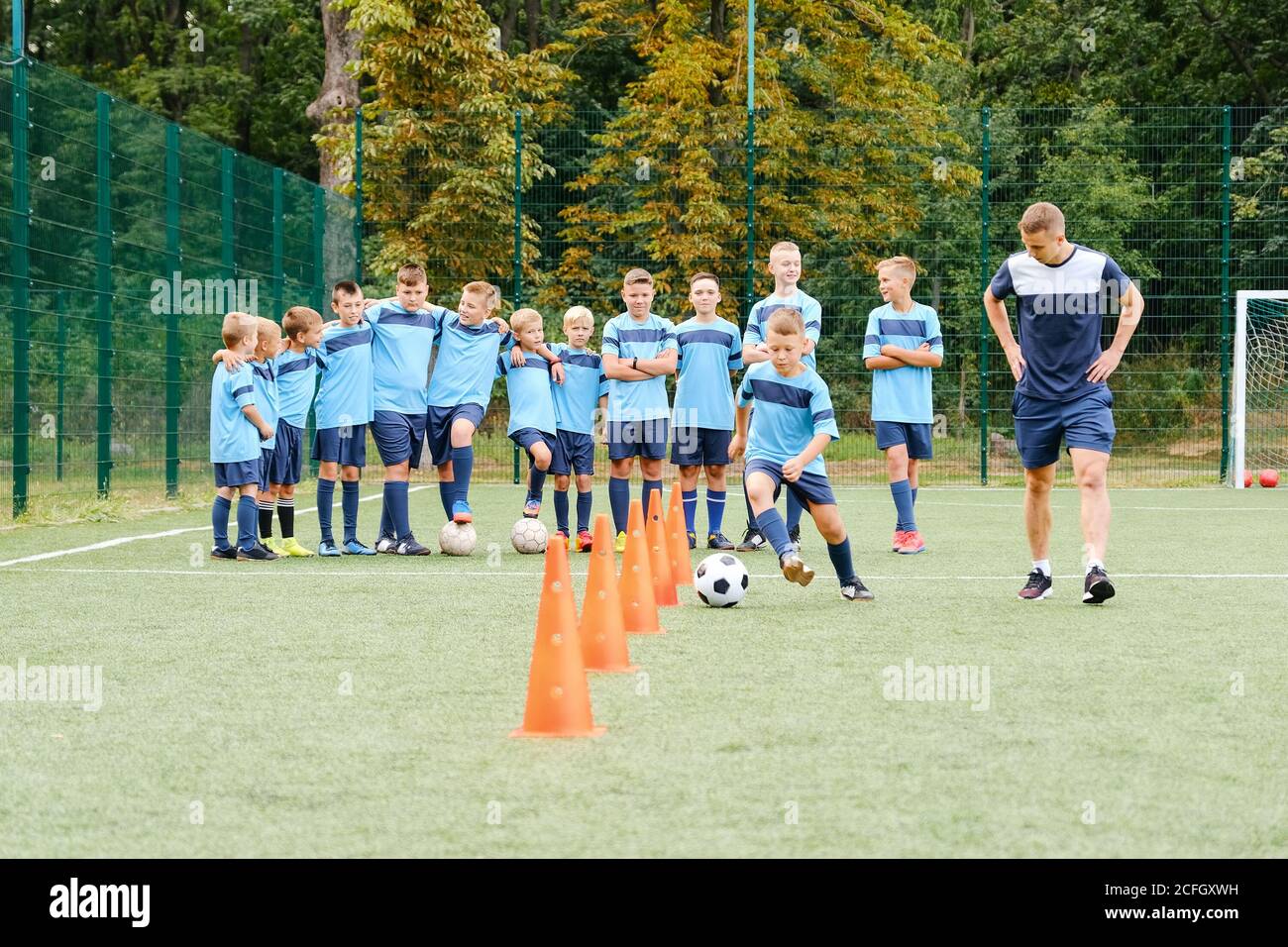 Kids player run and kick soccer balls between soccer chips in soccer ...