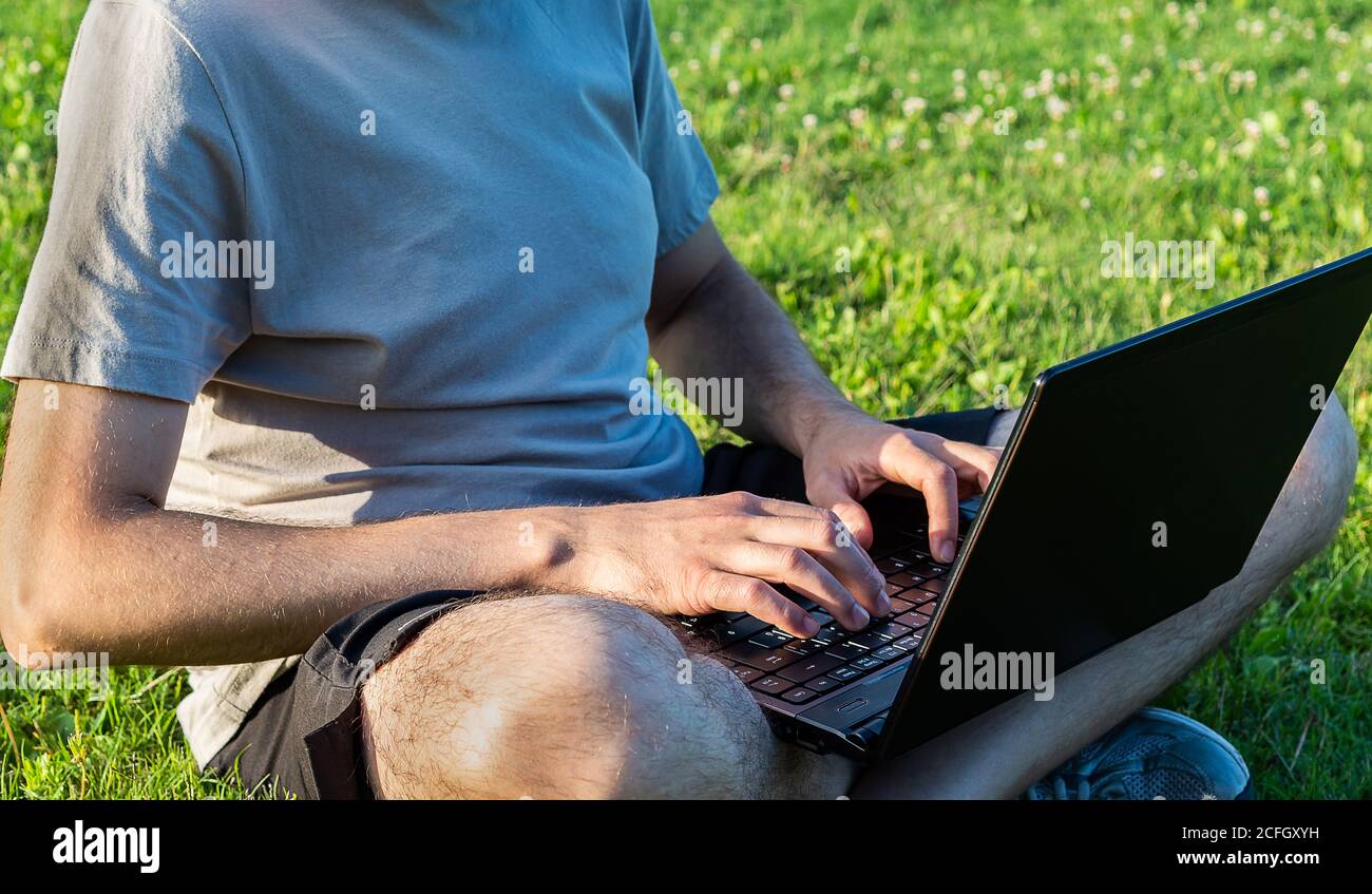 young man sitting on grass and working with laptop Stock Photo - Alamy