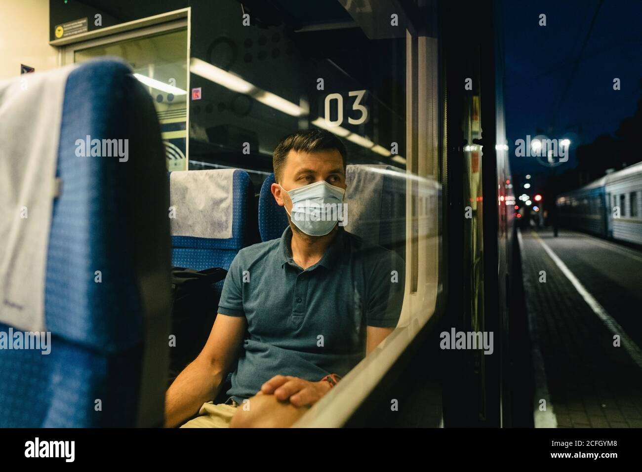 Tired and sad male passenger sits in face shield and looks through the ...