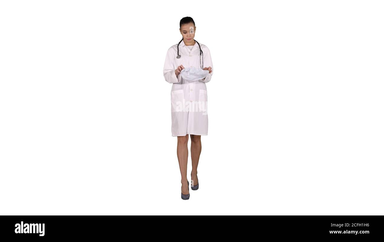 Medical doctor with stethoscope putting medical hat or cap on on white ...