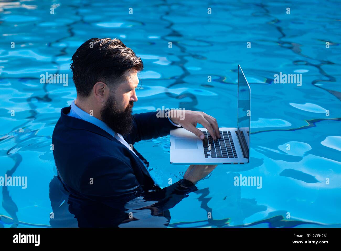 Business man in suit working on laptop from the swimming pool. Funny ...