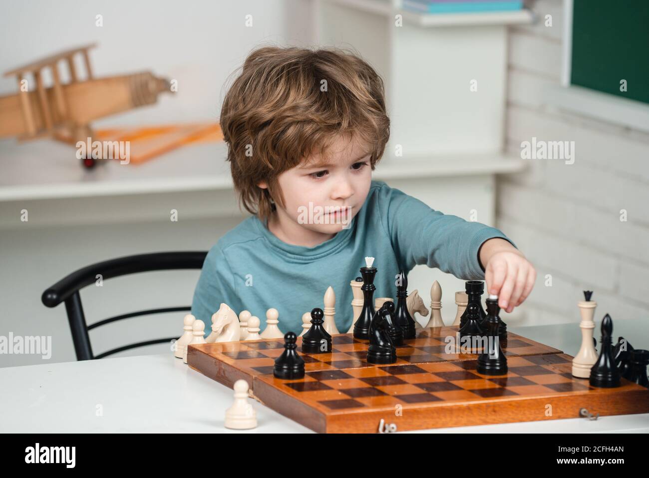 Little boy playing chess. Pupil kid thinking about his next move in a ...