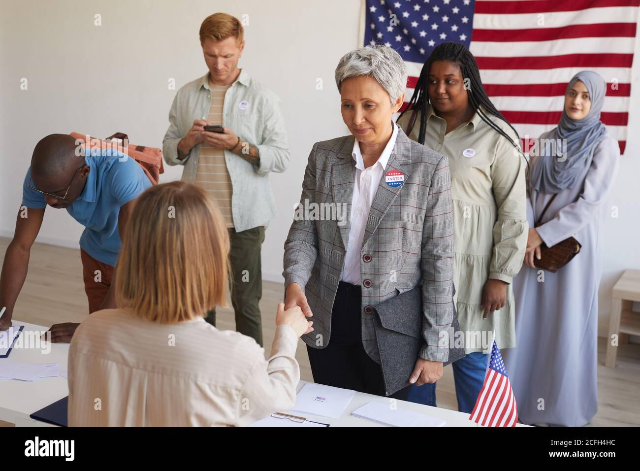 Multi-ethnic group of people at polling station decorated with American ...