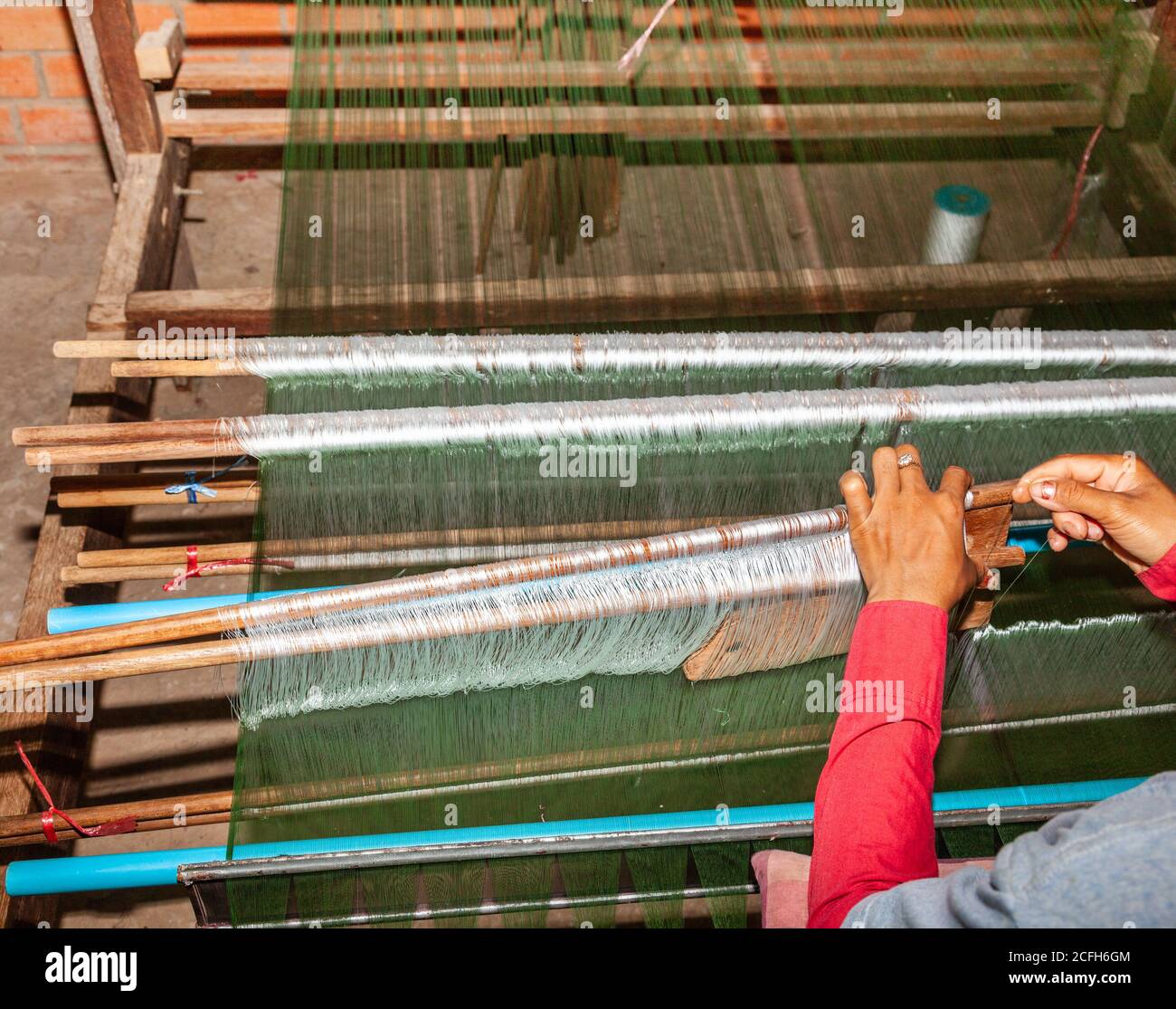working a loom, scene in silk factory in Cambodia. Silk direct from the ...