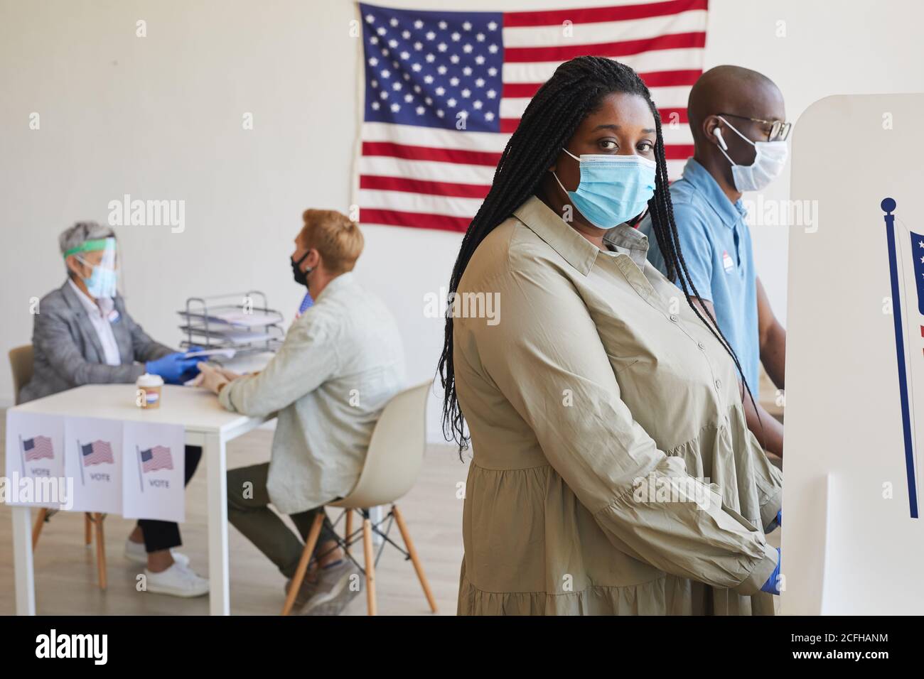 Side view portrait of female African-American voter standing in booth ...