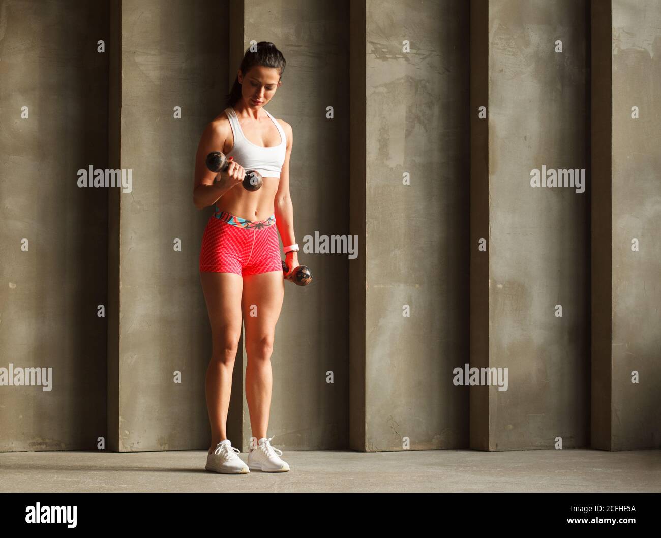 athletic woman doing lateral raise exercise for shoulders in sunny gym ...