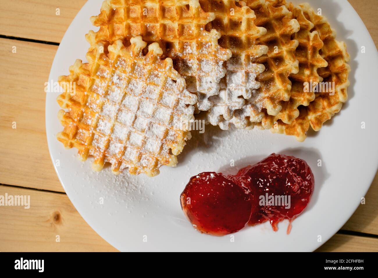 round belgian waffles on a white plate on a rustic wooden table Stock ...