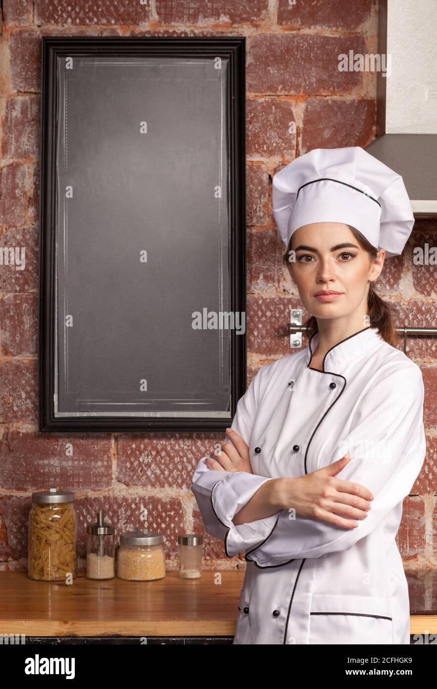 Female chef cook standing in the kitchen in white near blank black ...