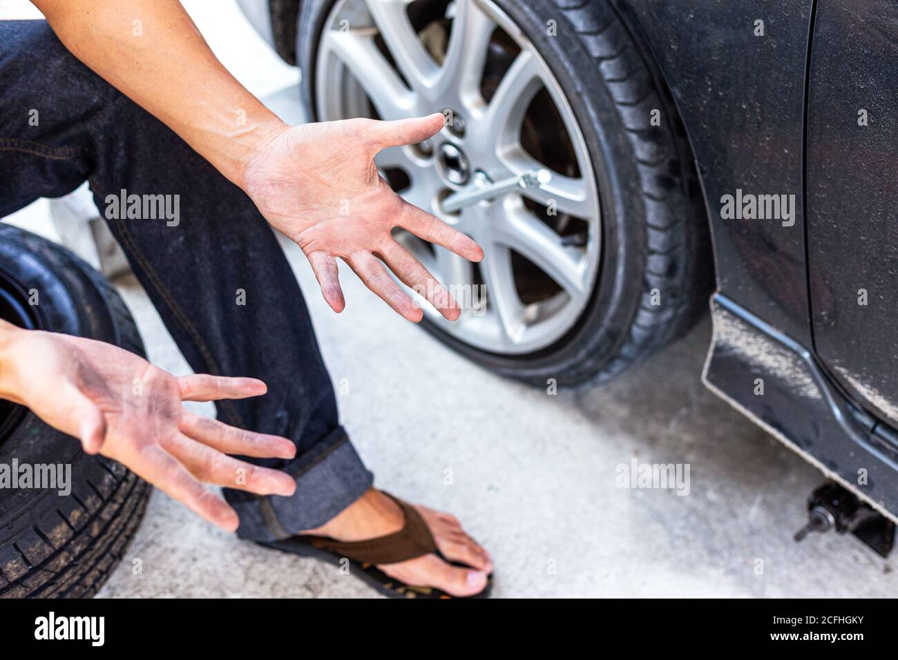 Man show hands of dirty after change a flat car tire at car park with ...