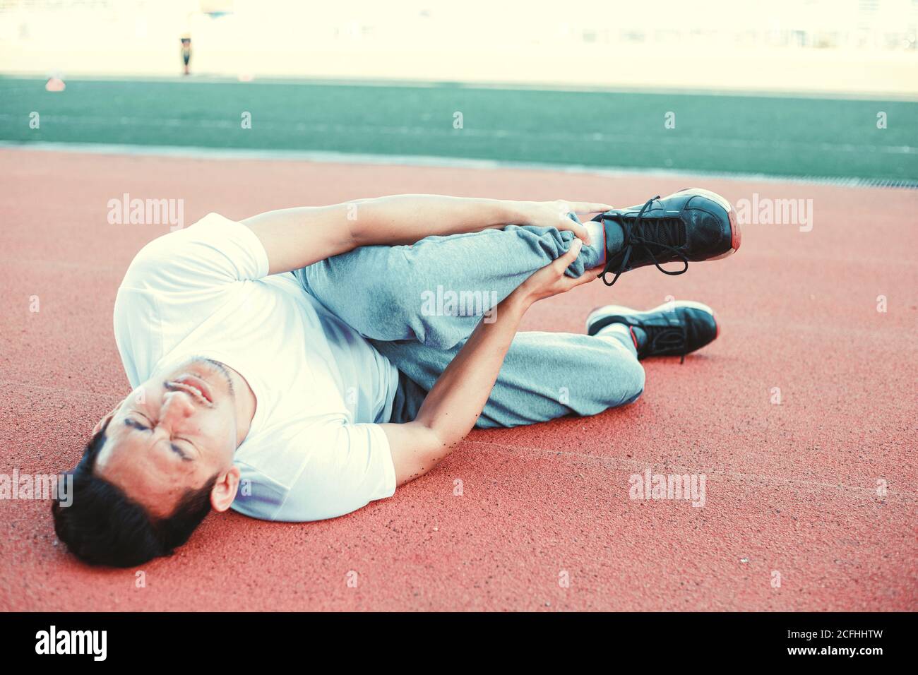 Twisted ankle. Young runner touching his sprained leg between jogger at ...