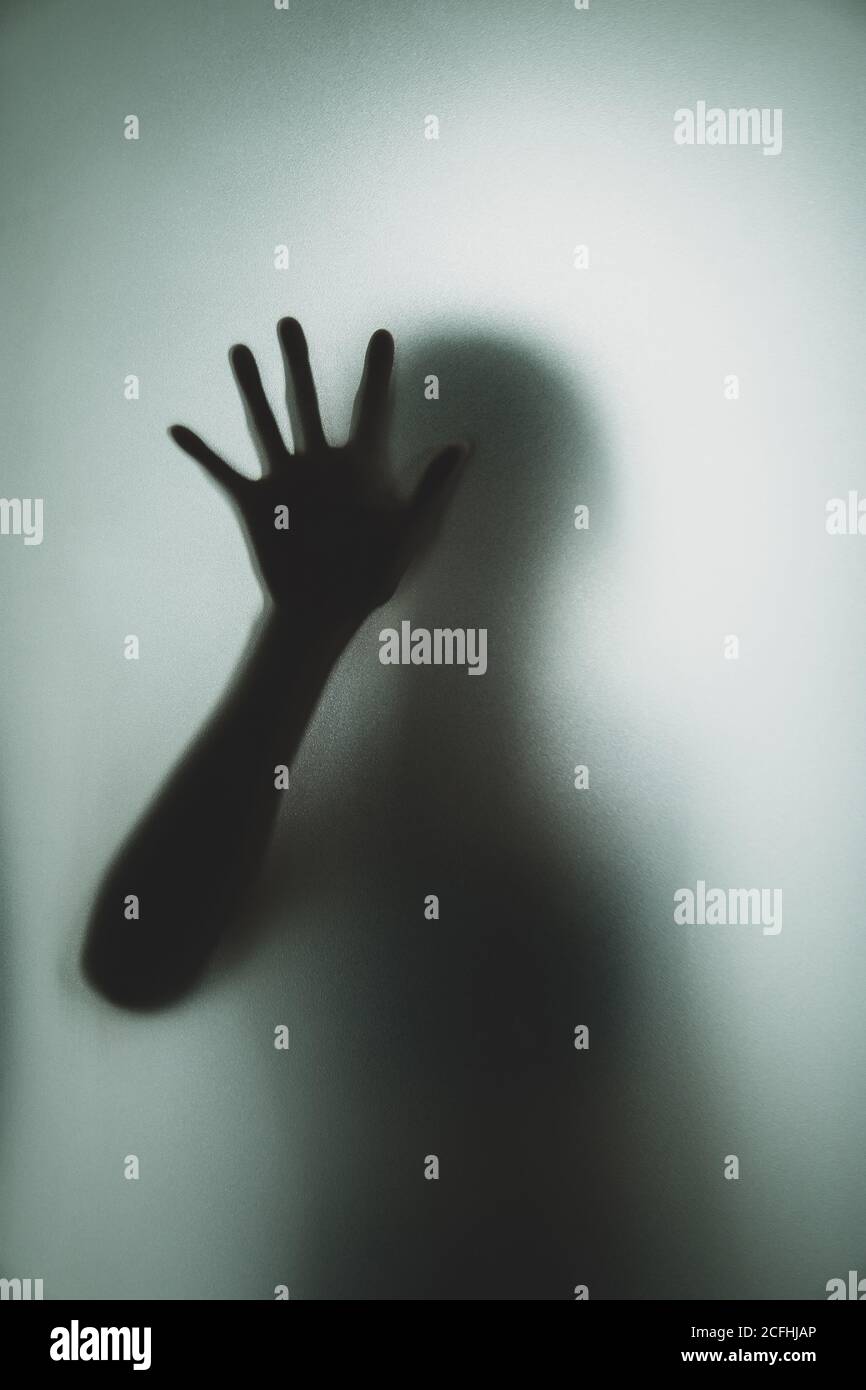 Ghost concept shadow of a woman behind the matte glass blurry hand and ...