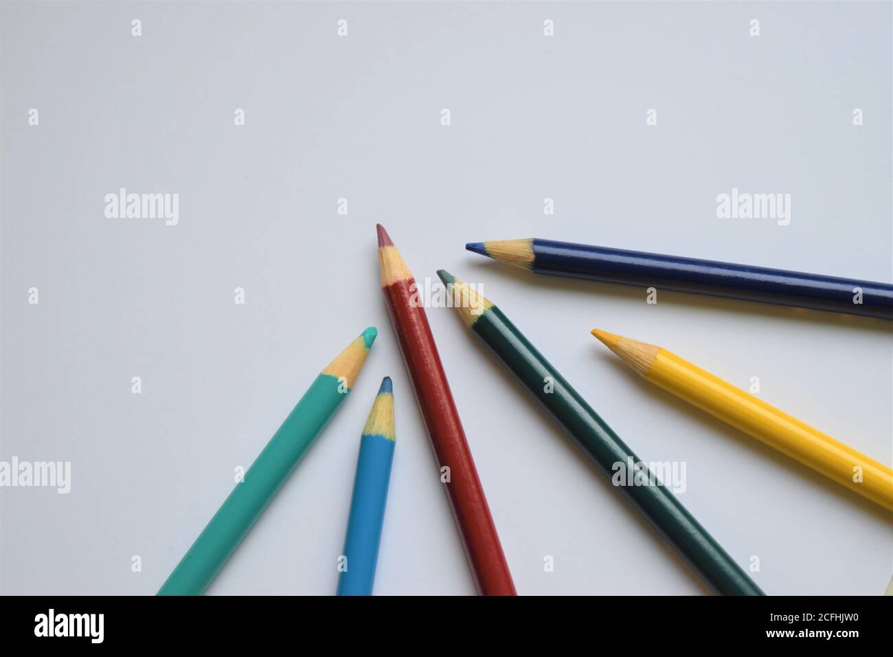 Sharp colored pencils arranged on a white background with copy space ...