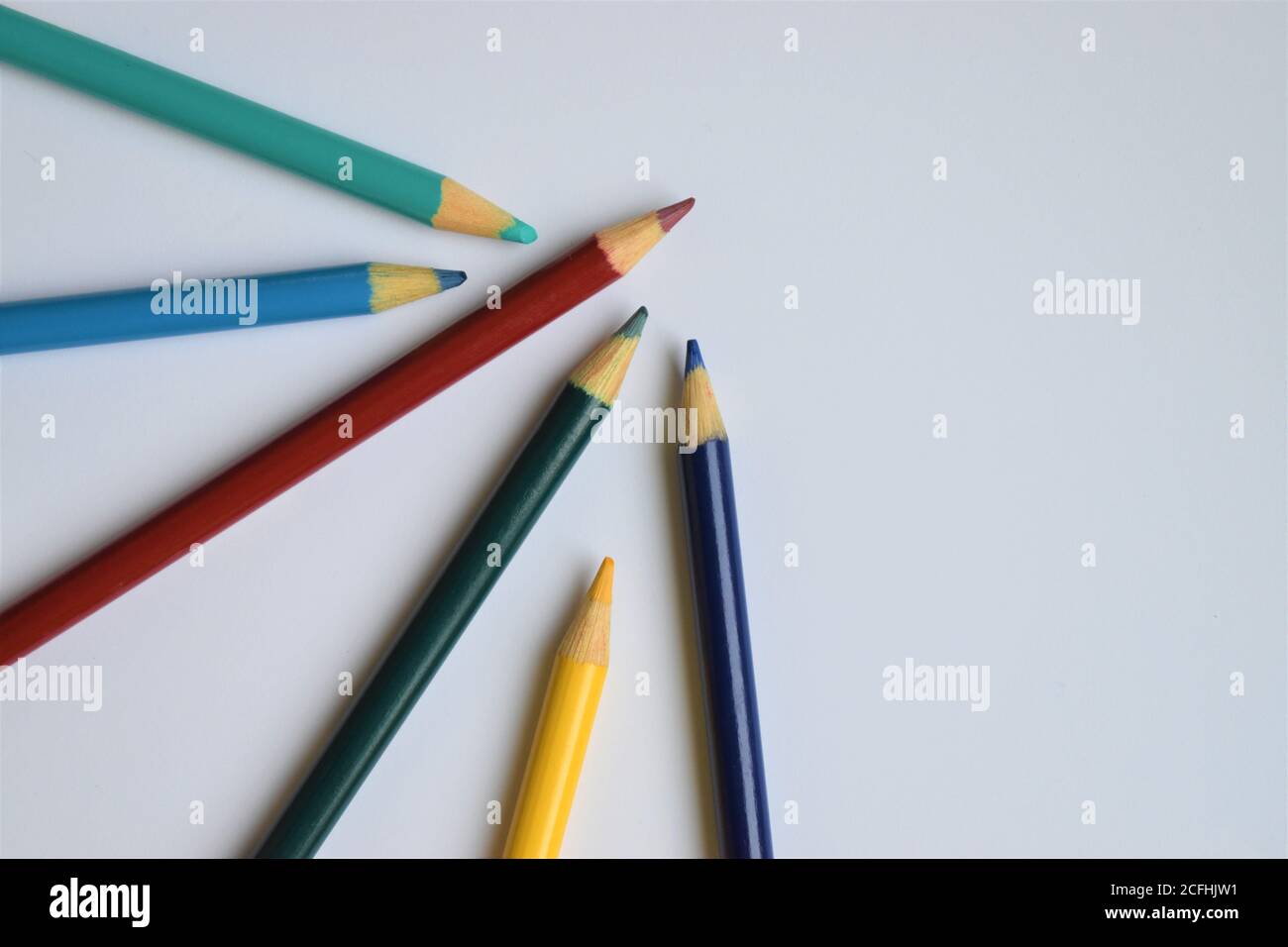 Sharp colored pencils arranged on a white background with copy space ...