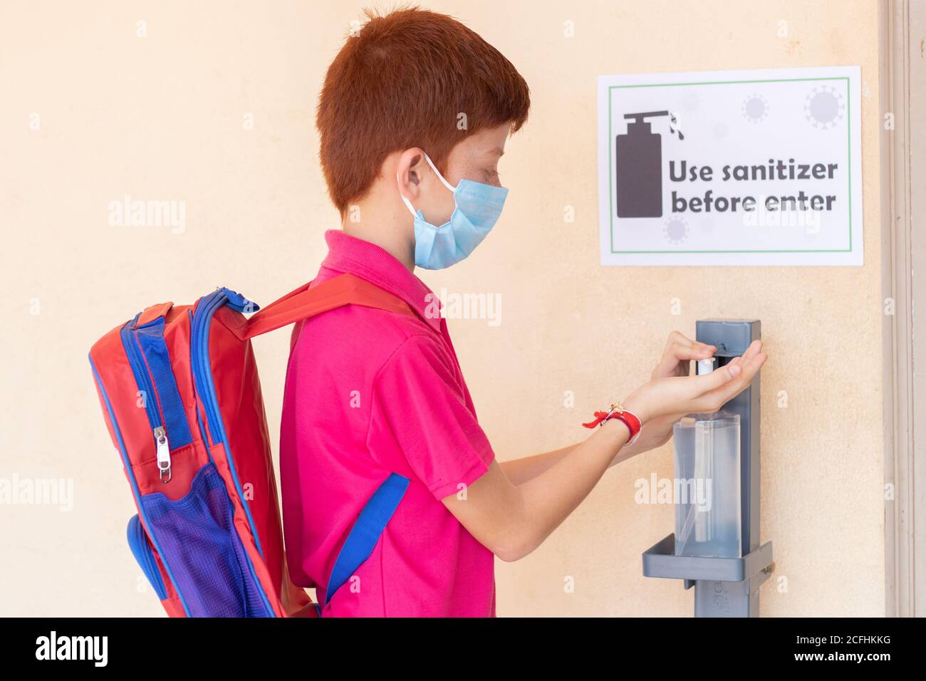 Kid with medical mask using hand sanitizer before entering classroom ...