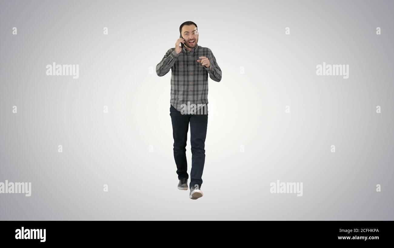 Serious man walking and talking on his cellphone on gradient background ...