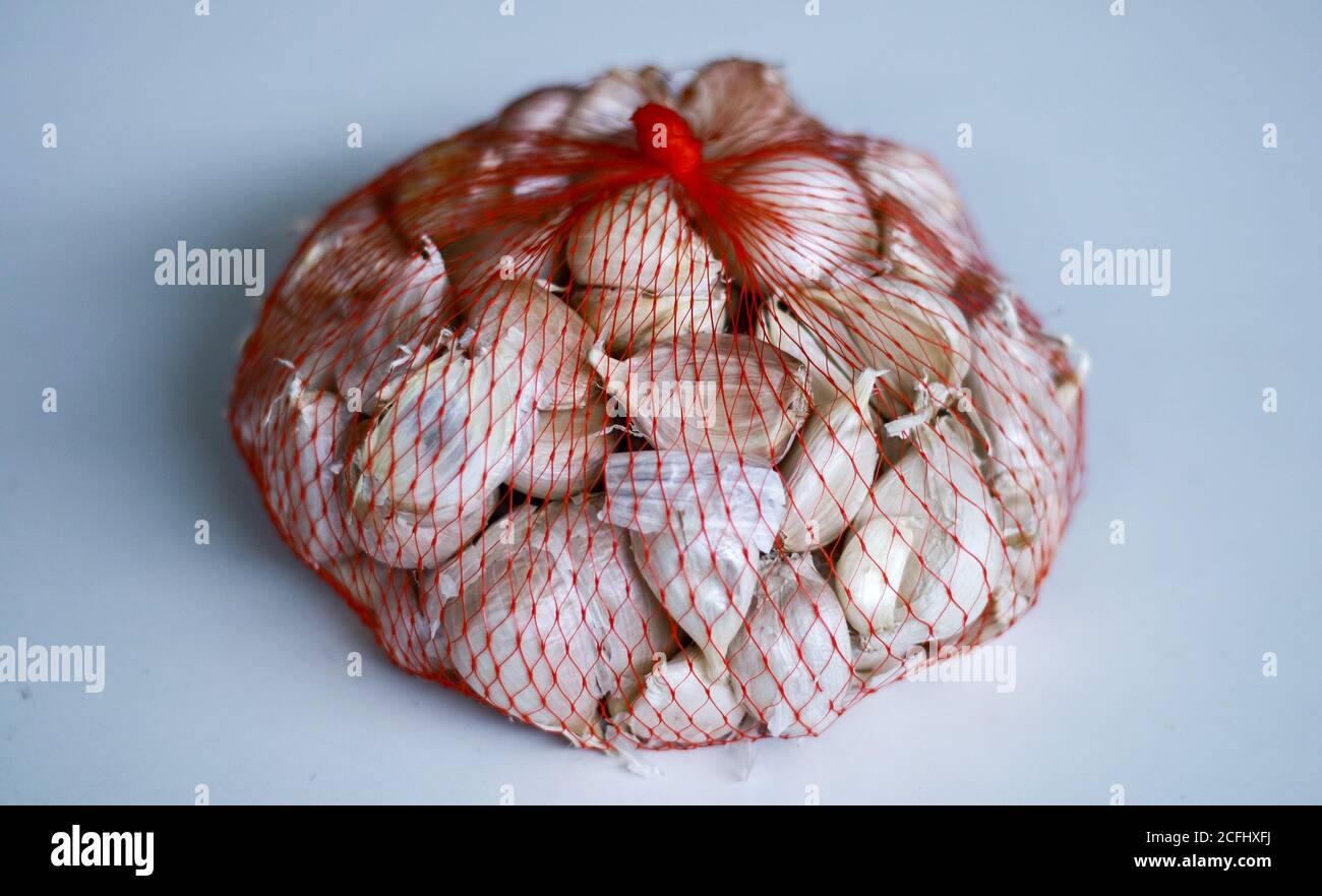 Garlic in a mesh bag on white background Stock Photo - Alamy