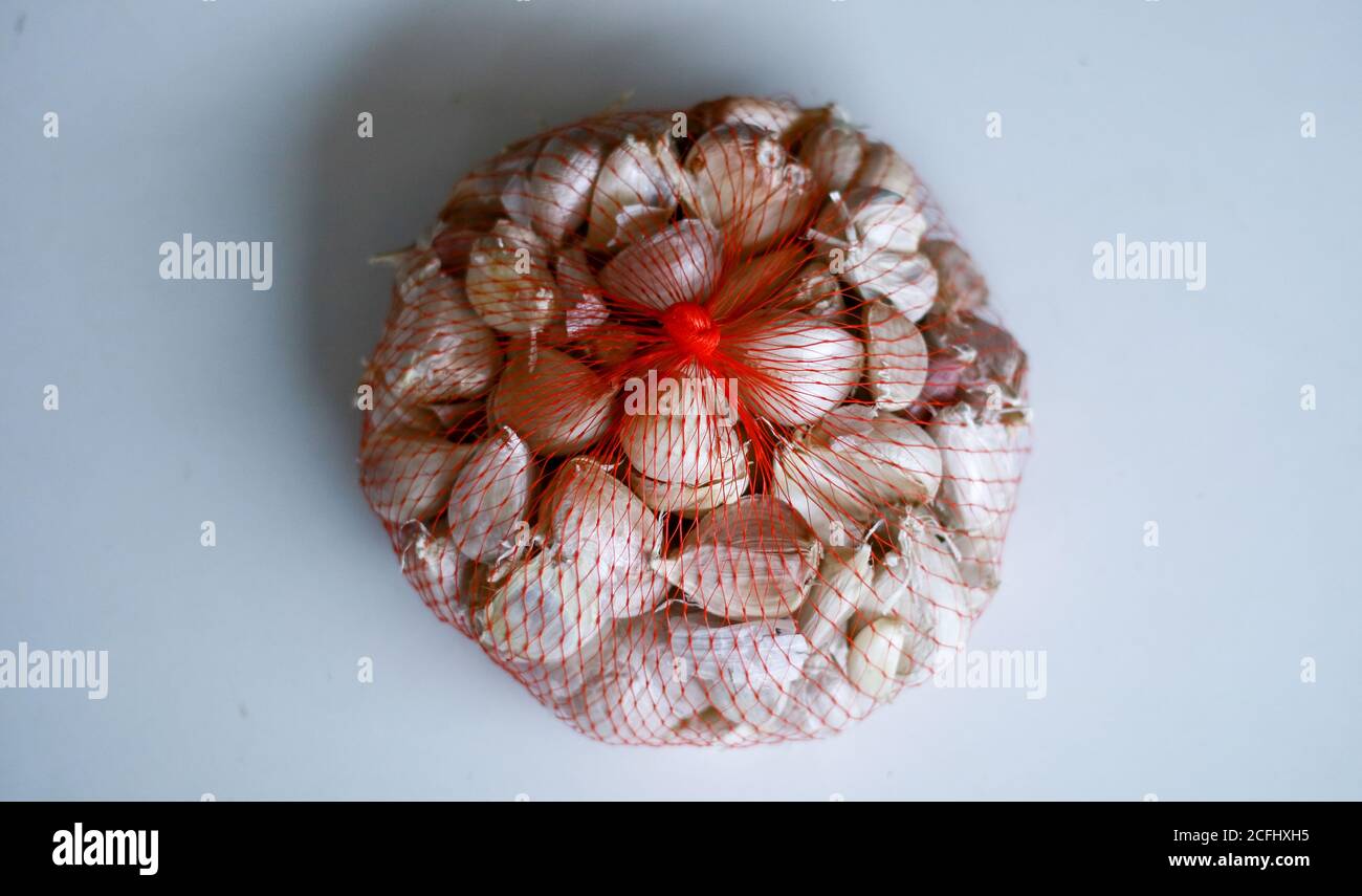 Garlic in a mesh bag on white background Stock Photo - Alamy