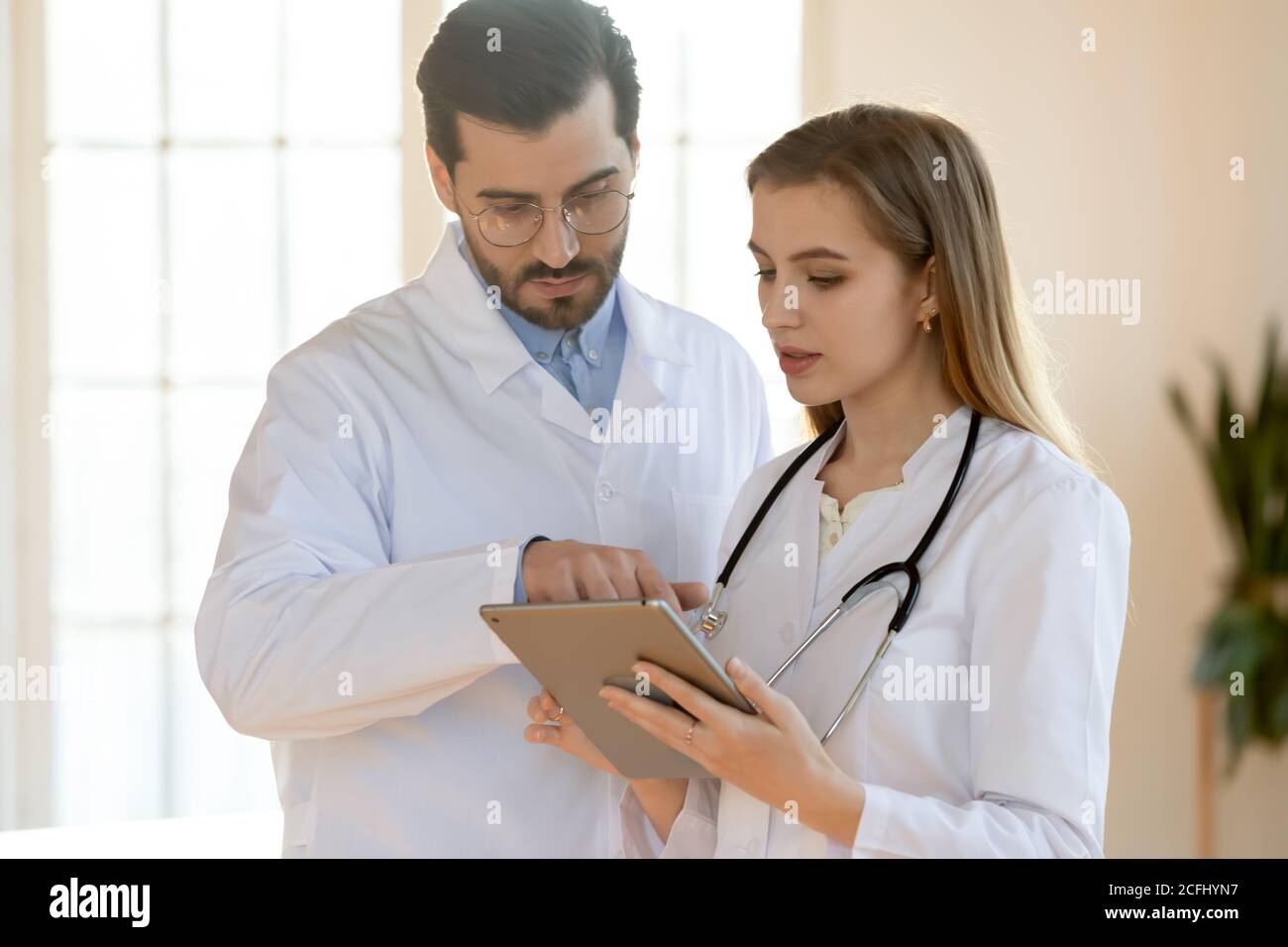 Confident doctor and young nurse talking, working together, using ...