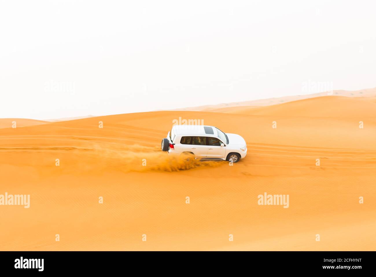 4x4 jeep car riding through the Arabian golden desert sand dunes during ...