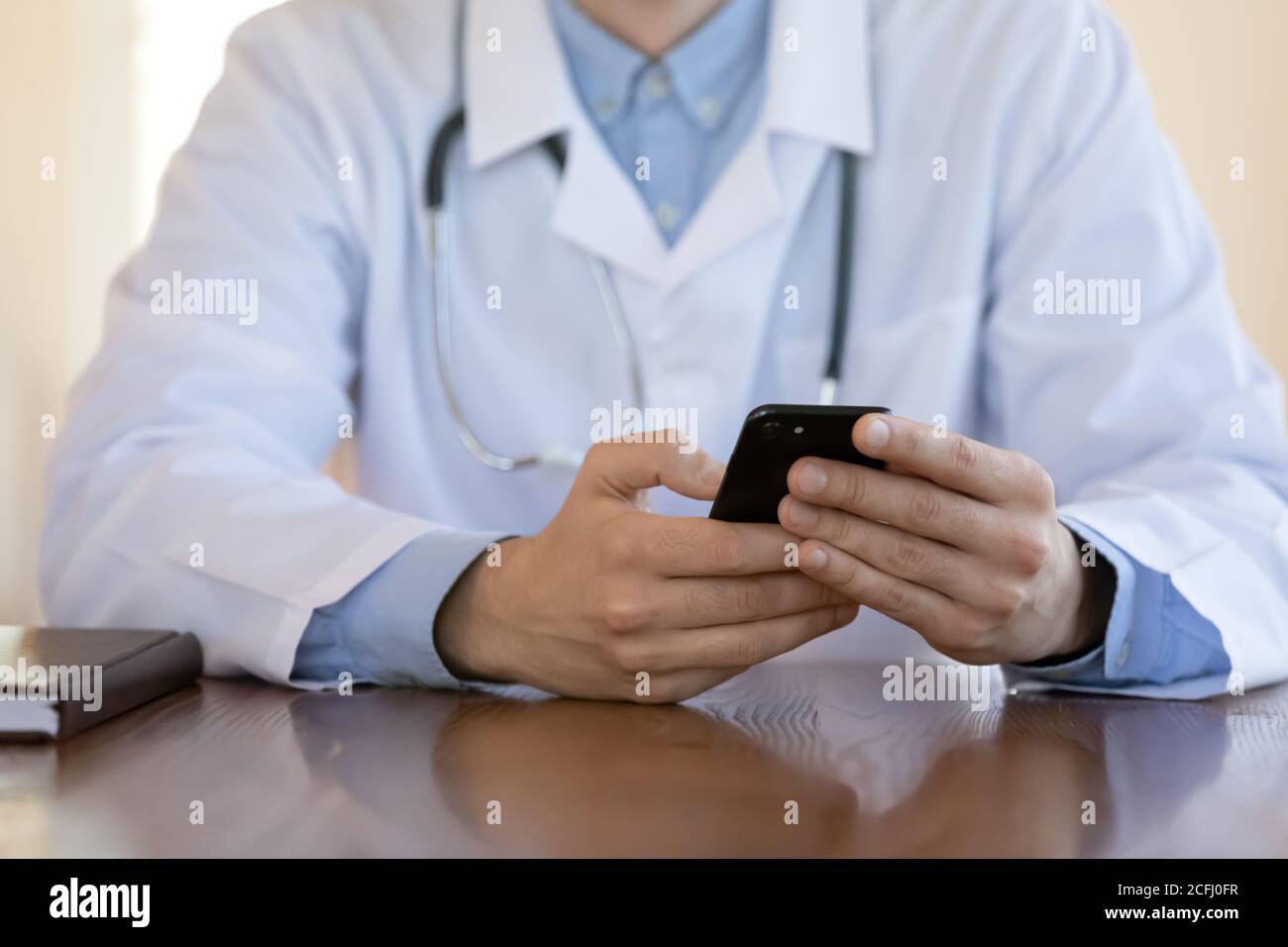 Close up doctor wearing uniform holding phone, using medical apps Stock ...