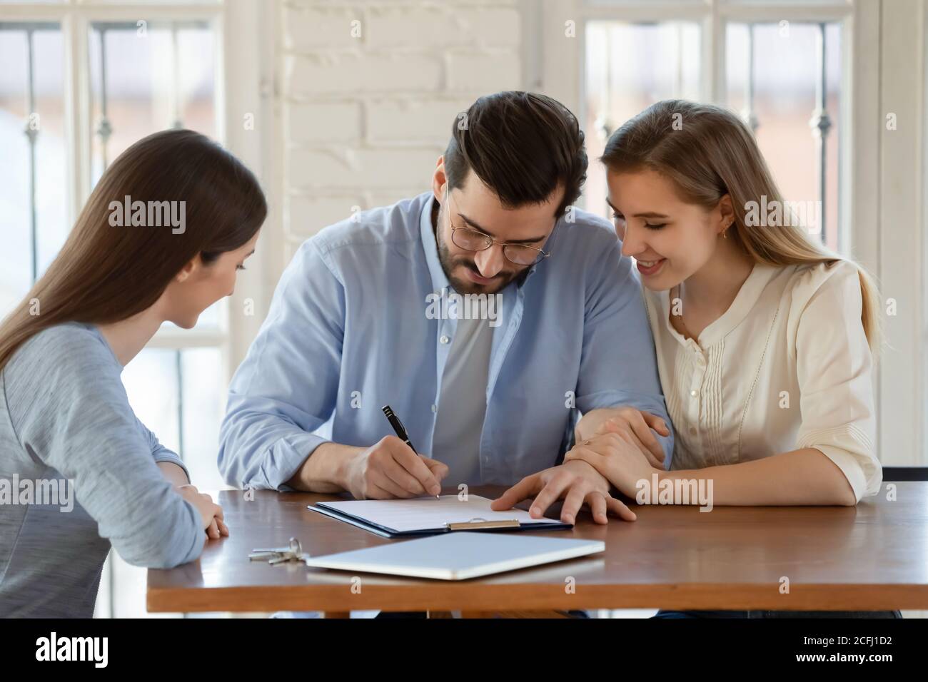 Happy young married couple signing contract, making successful deal ...
