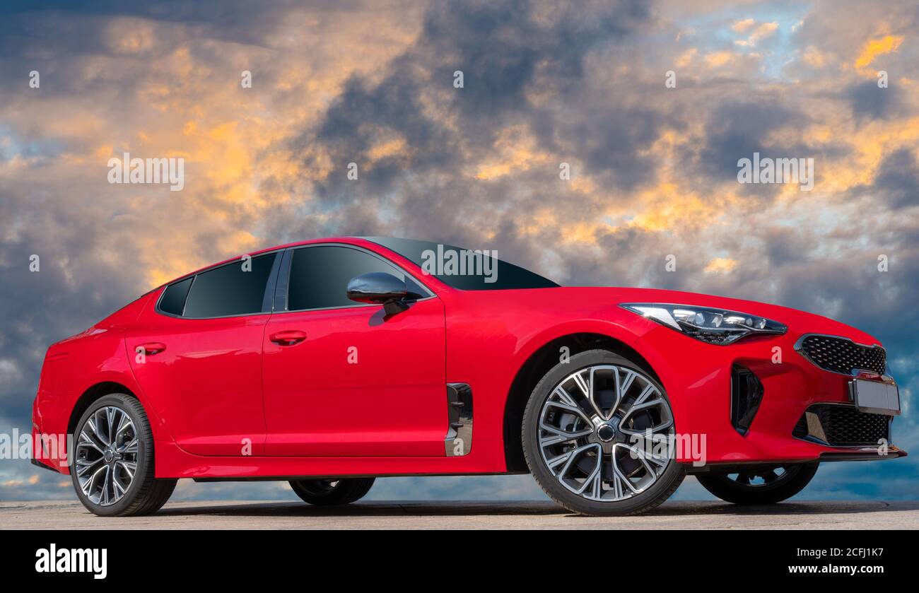 Modern red luxury car under the cloudy sunset sky Stock Photo - Alamy
