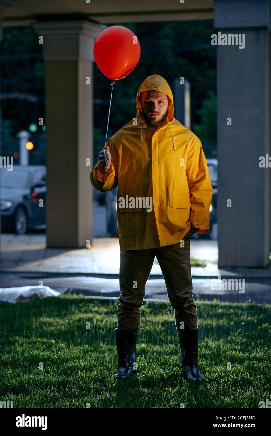 Scary man with balloon walking in night park Stock Photo - Alamy