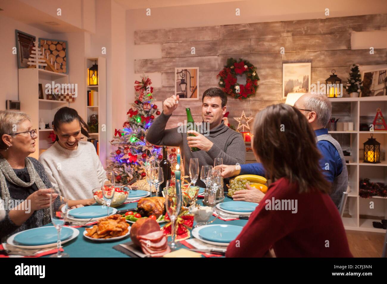 Happy father opening a bottle of wine at christmas family dinner ...