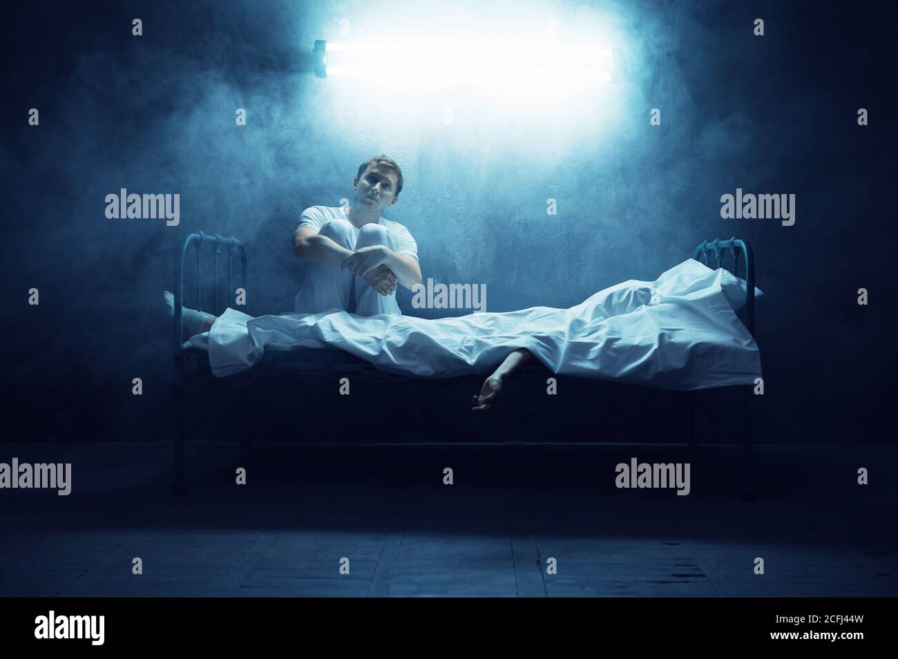 Psycho man sitting in bed near dead woman Stock Photo - Alamy
