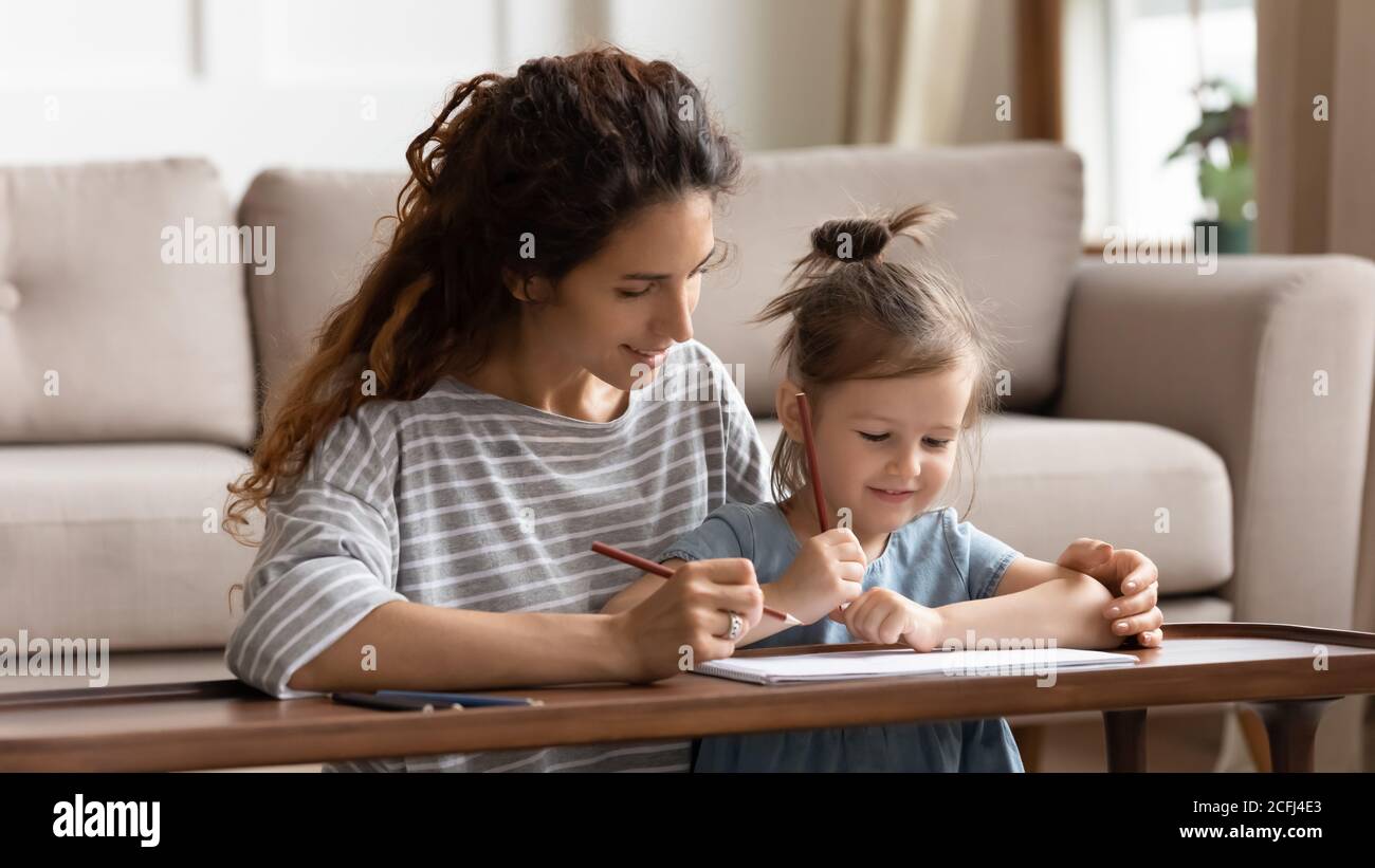 Mom teach daughter to draw on paper with colorful pencil Stock Photo ...