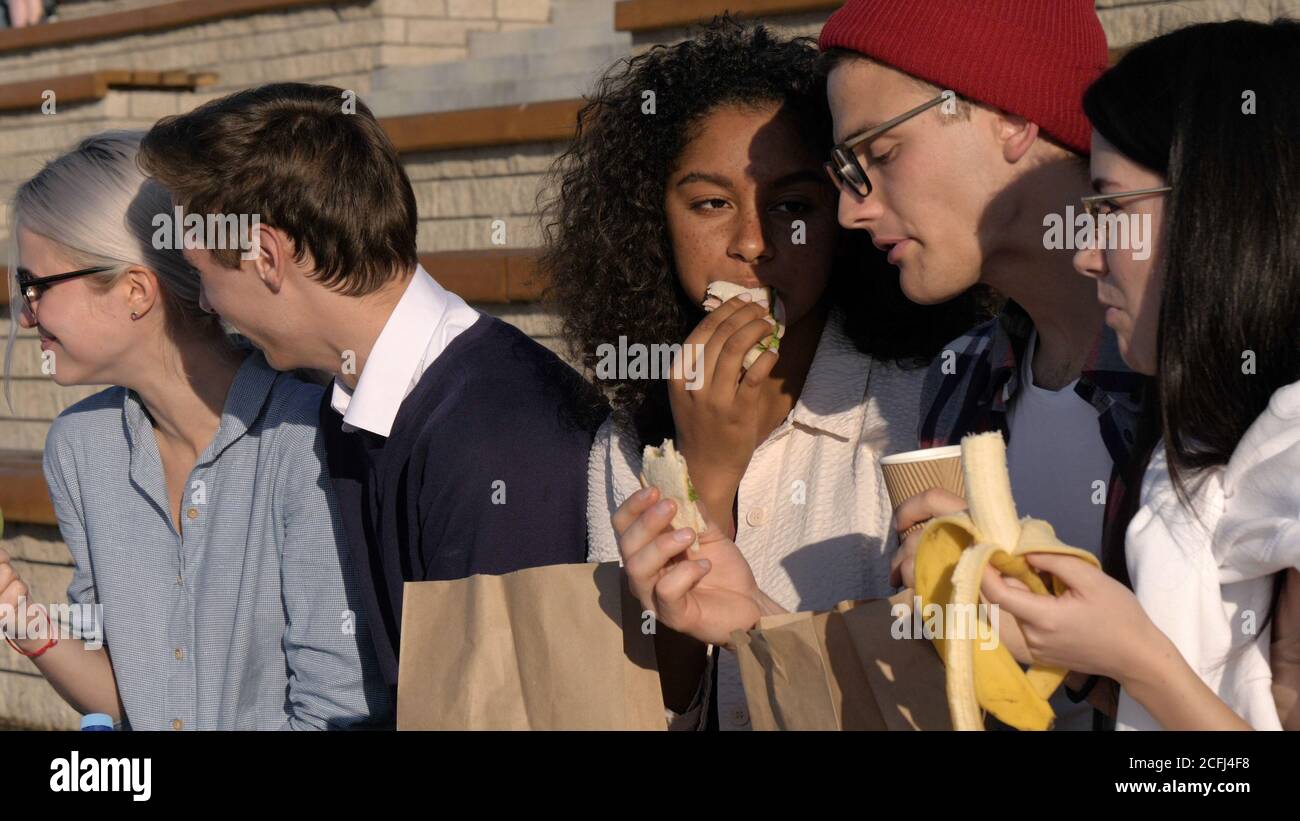 Happy millennial friends eating sandwiches outdoors Stock Photo - Alamy