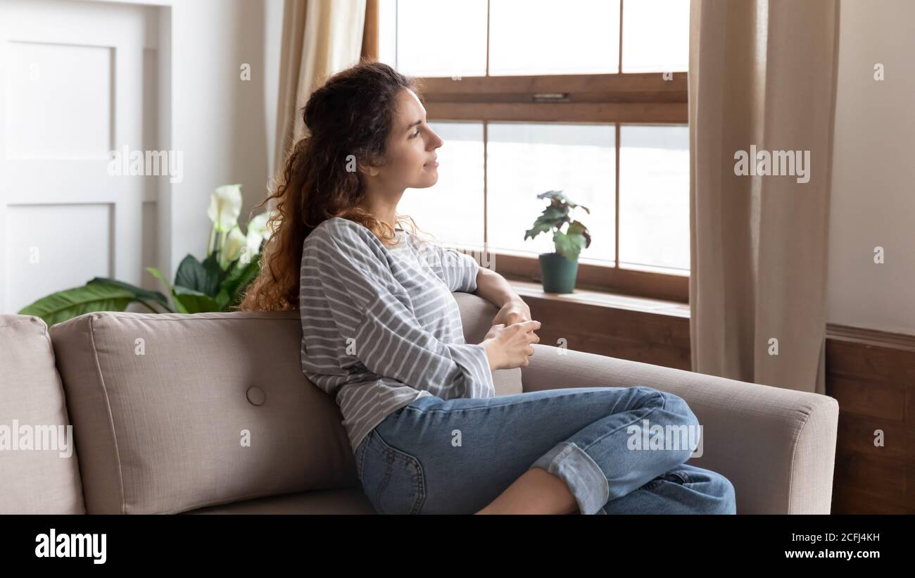 Beautiful pensive woman looking out window while resting on couch Stock ...